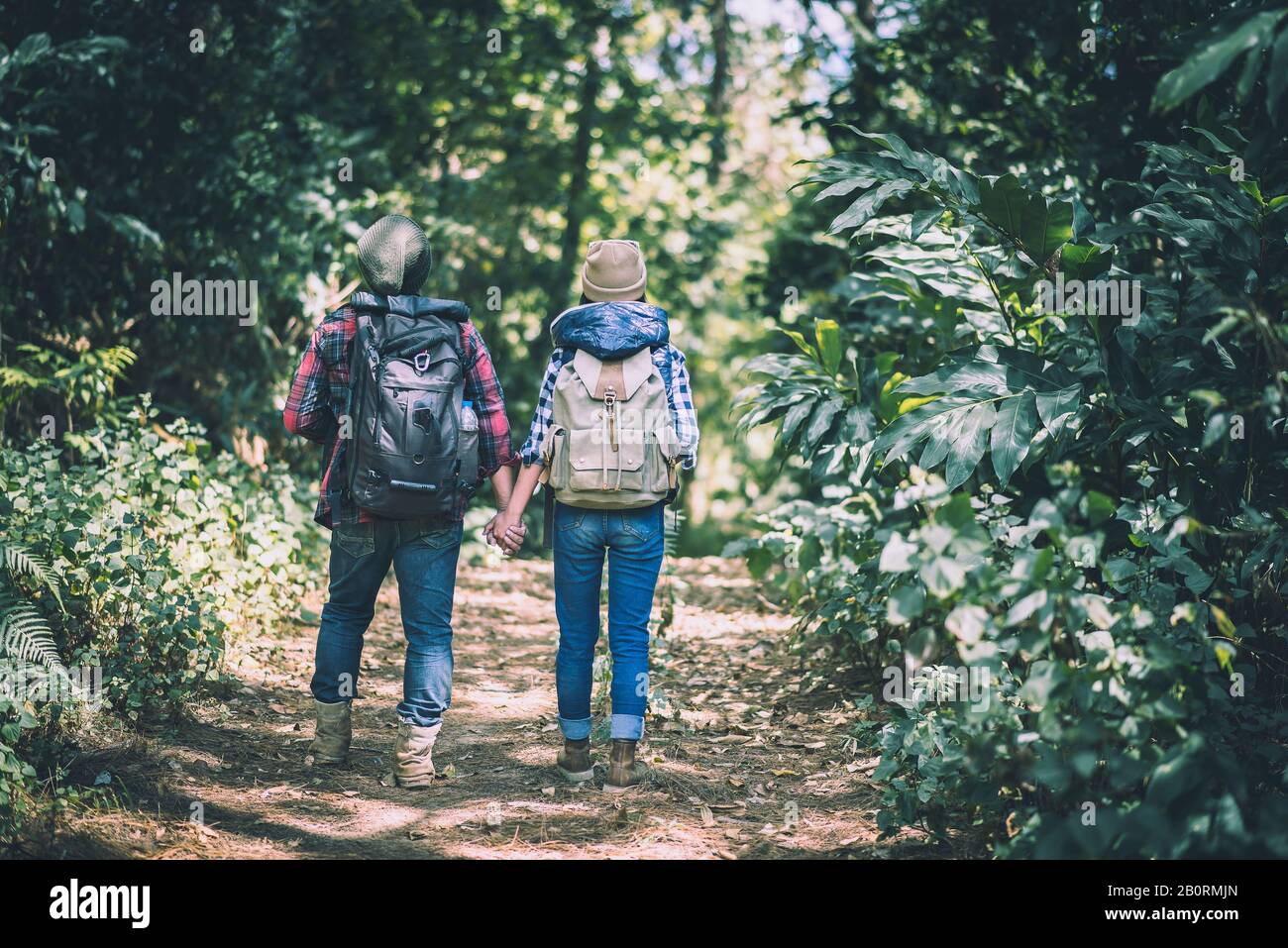 Young couple walking with backpacks in forest. Adventure hikes Stock ...