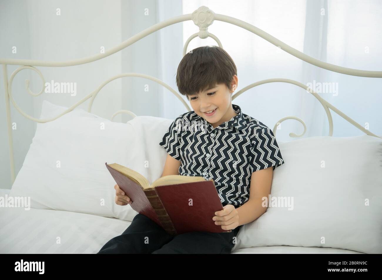 Young boy reading book on bed at home Stock Photo - Alamy