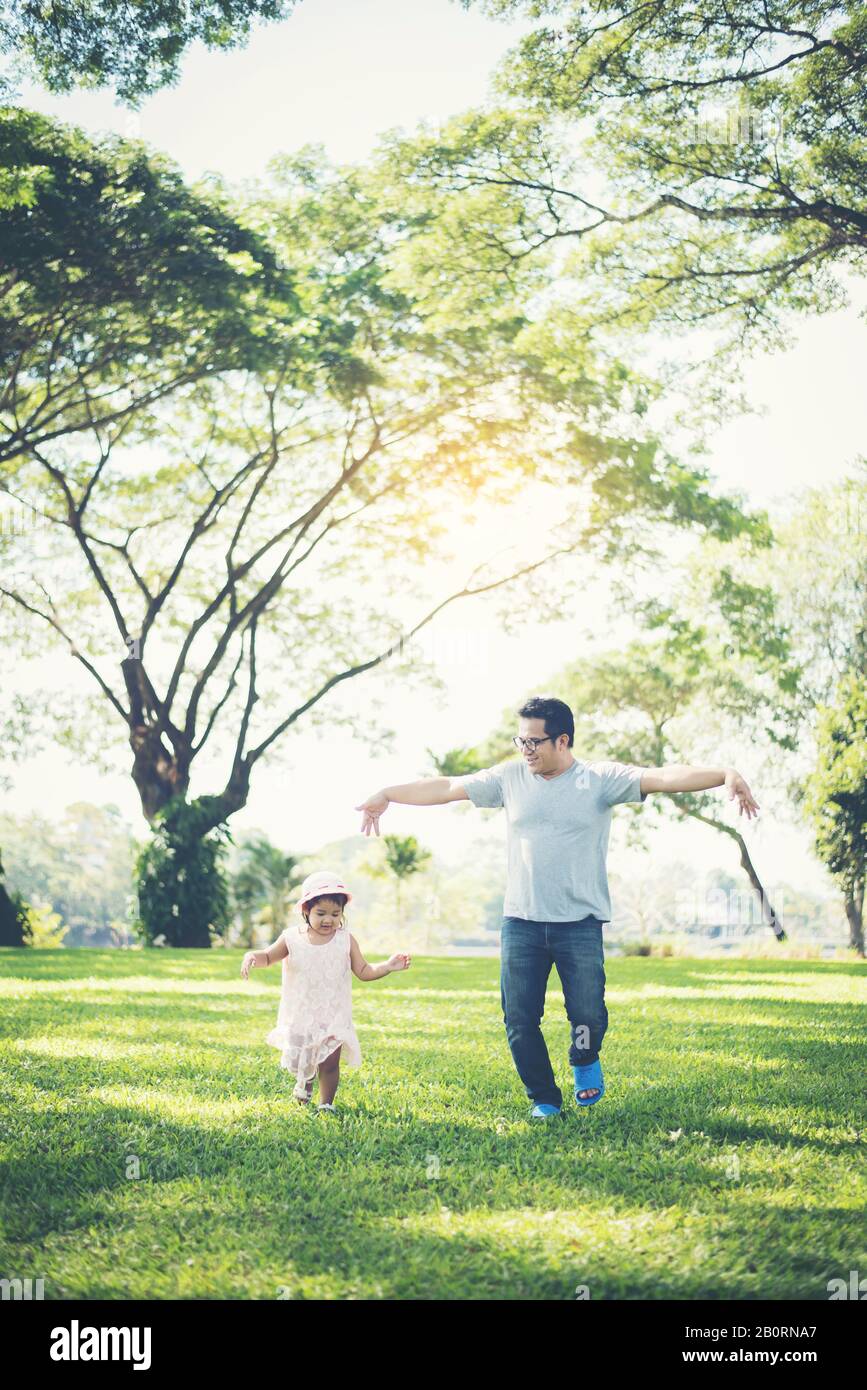 Toddler girl holding hands with her father walking in the park, happiness time Stock Photo - Alamy