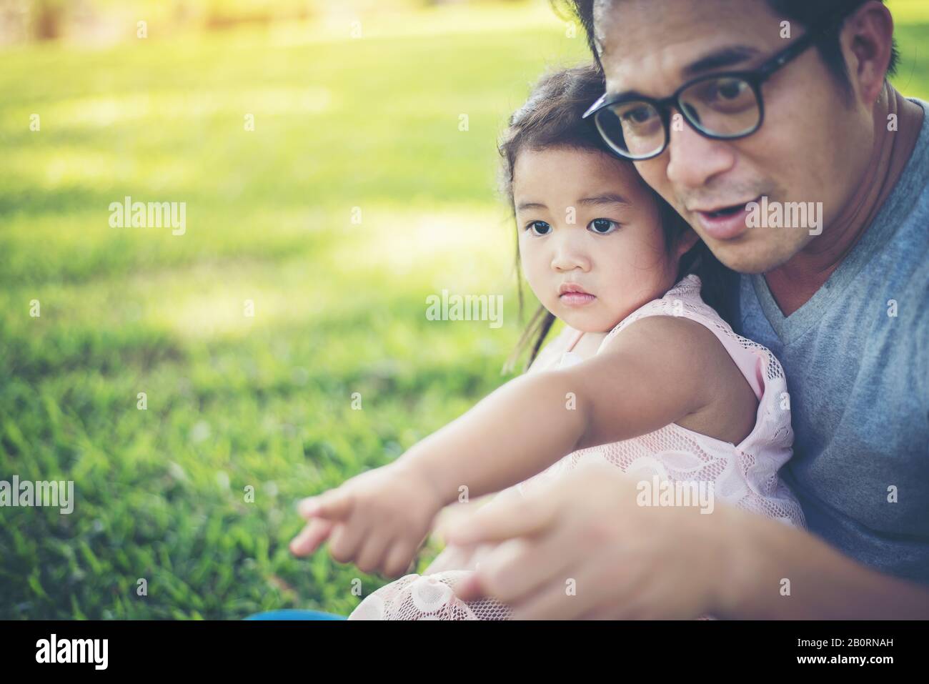 happy father and daughter pointing with finger and looking at something ...