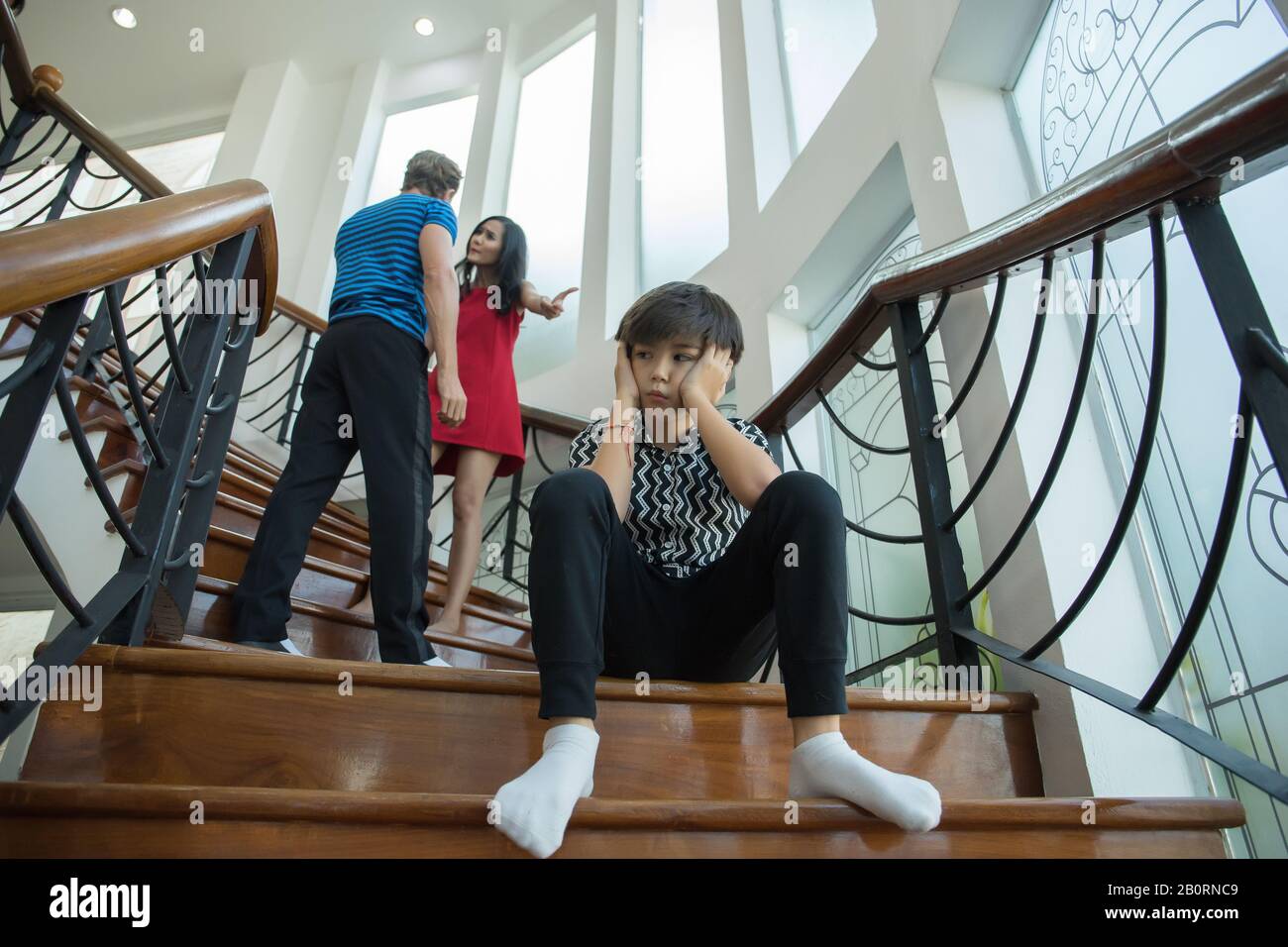 The boy is closing his ears between parents quarrel fighting. Stop ...