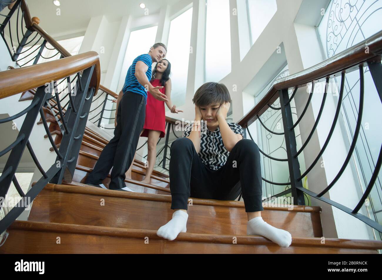 The boy is closing his ears between parents quarrel fighting. Stop ...