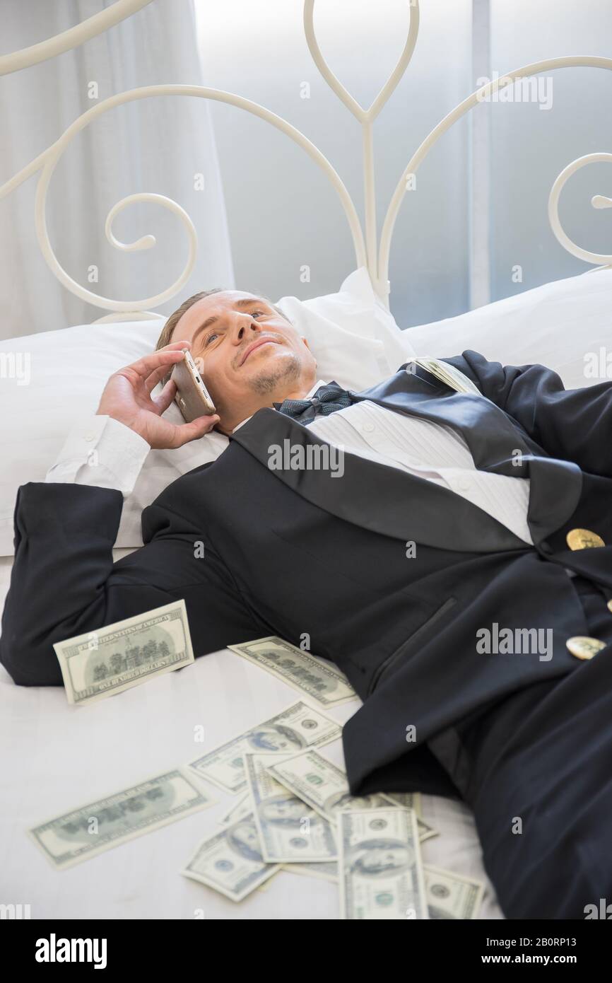 Rich man lying on the bed with dollar banknotes. Success business ...