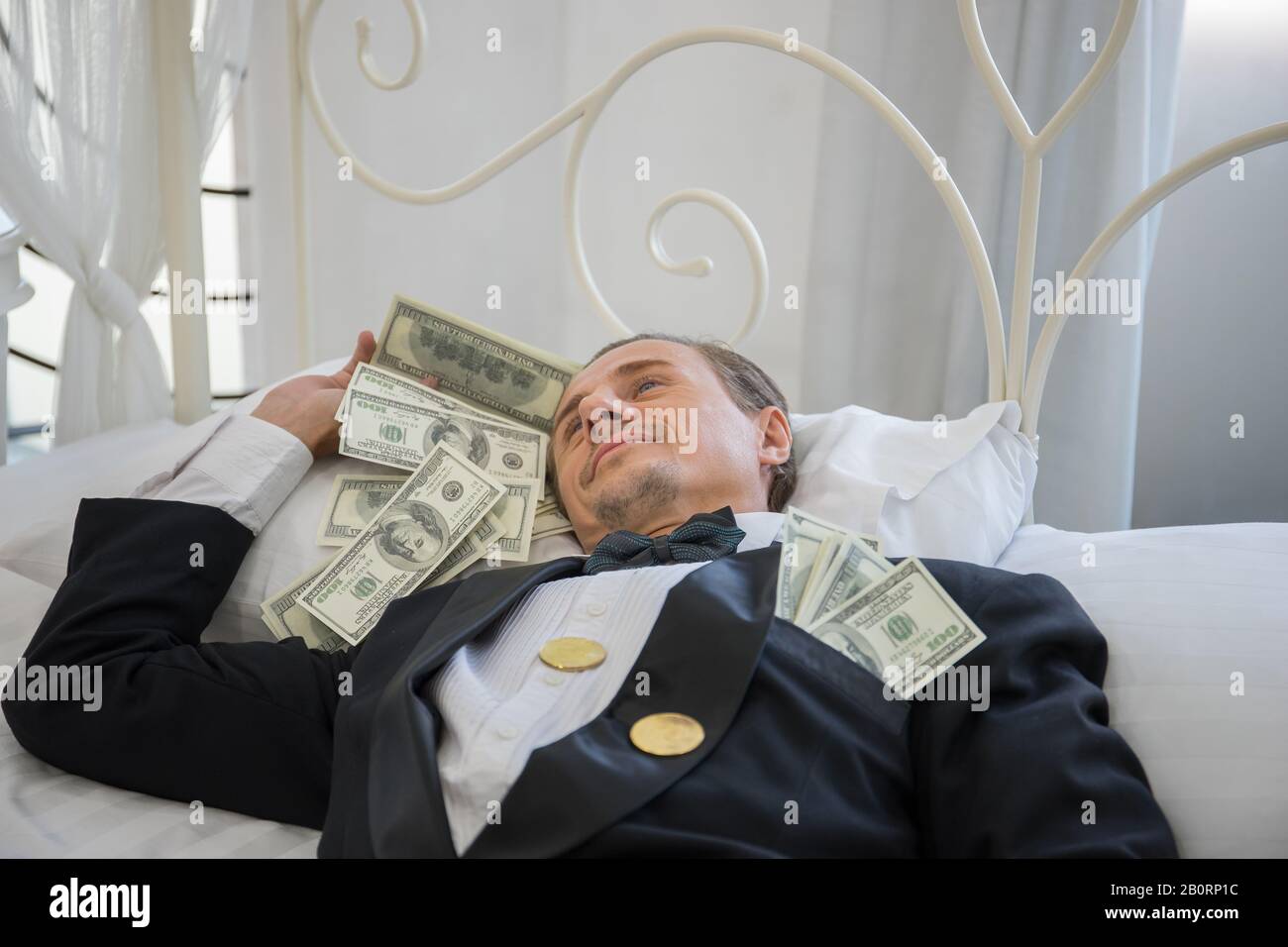 Rich man lying on the bed with dollar banknotes. Success business ...