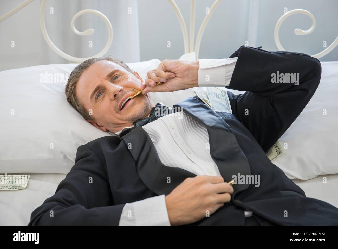 Rich man lying on the bed with dollar banknotes. Success business ...