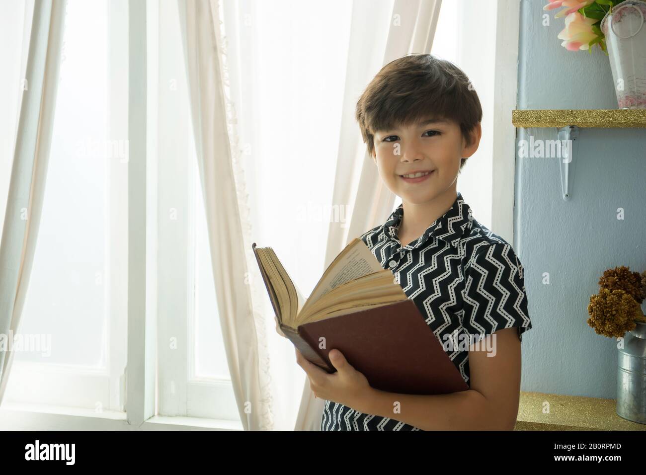 Boy reading a book in the room Stock Photo - Alamy