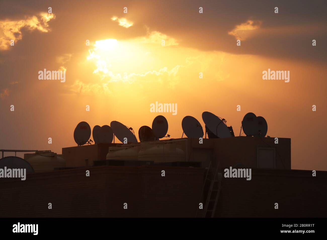 Satellite television dishes clustered on rooftop with rising sun hi-res ...