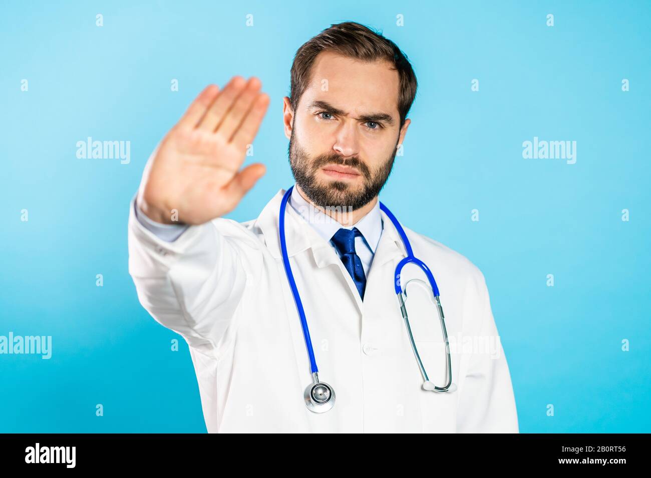 Portrait of serious doctor in professional medical white coat showing ...