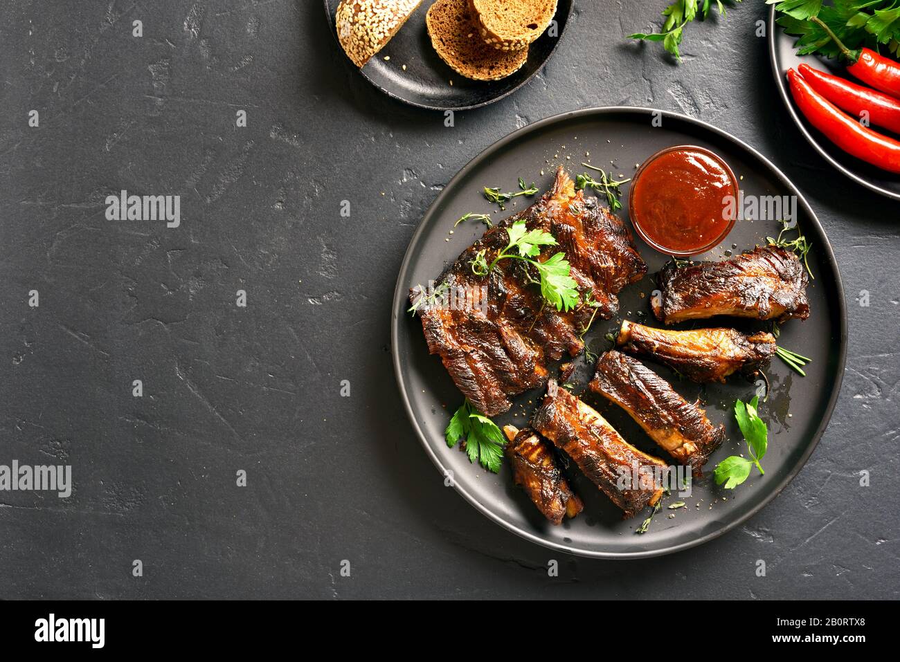 Spicy grilled spare ribs on plate over black stone background with free ...