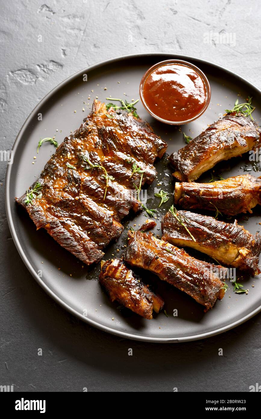 Grilled spare ribs on plate over black stone background. Tasty bbq meat ...