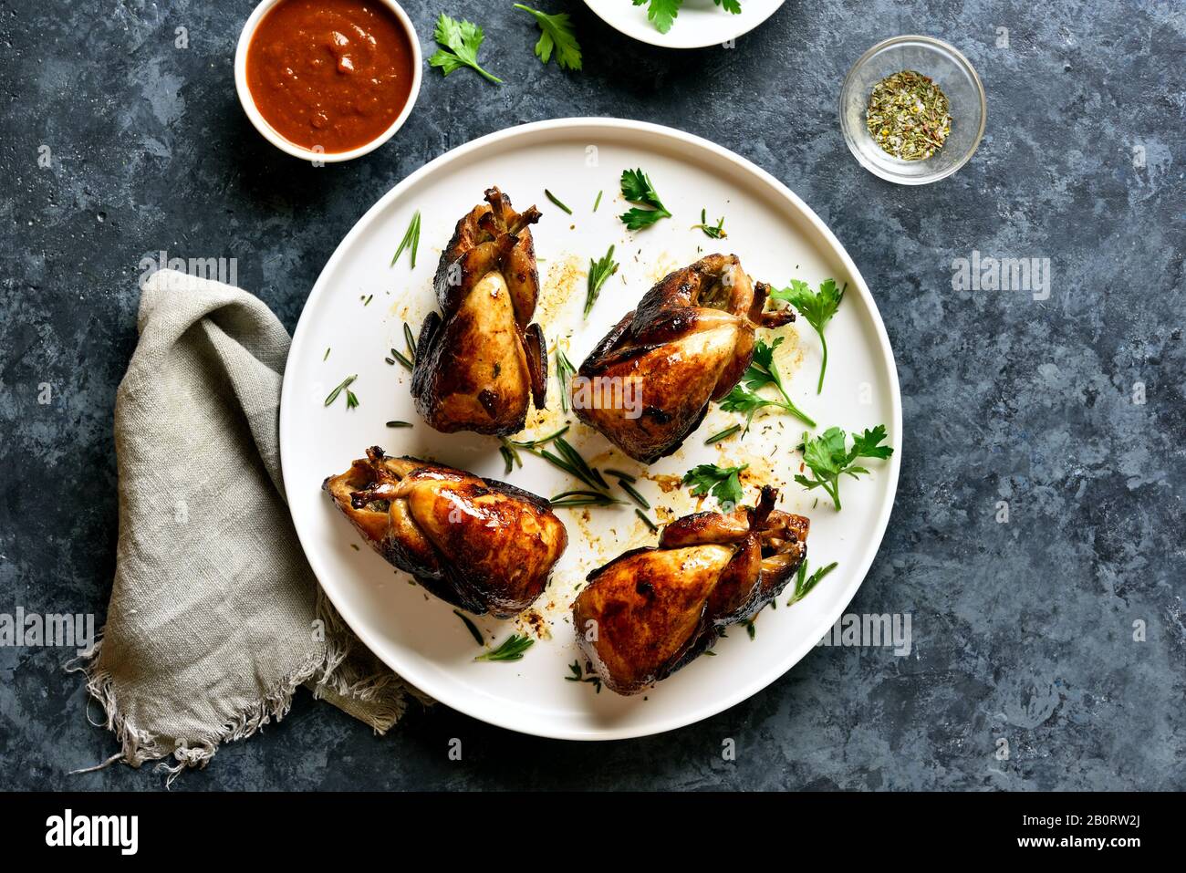 Roasted quails on white plate. Tasty grilled quails carcasses on blue ...