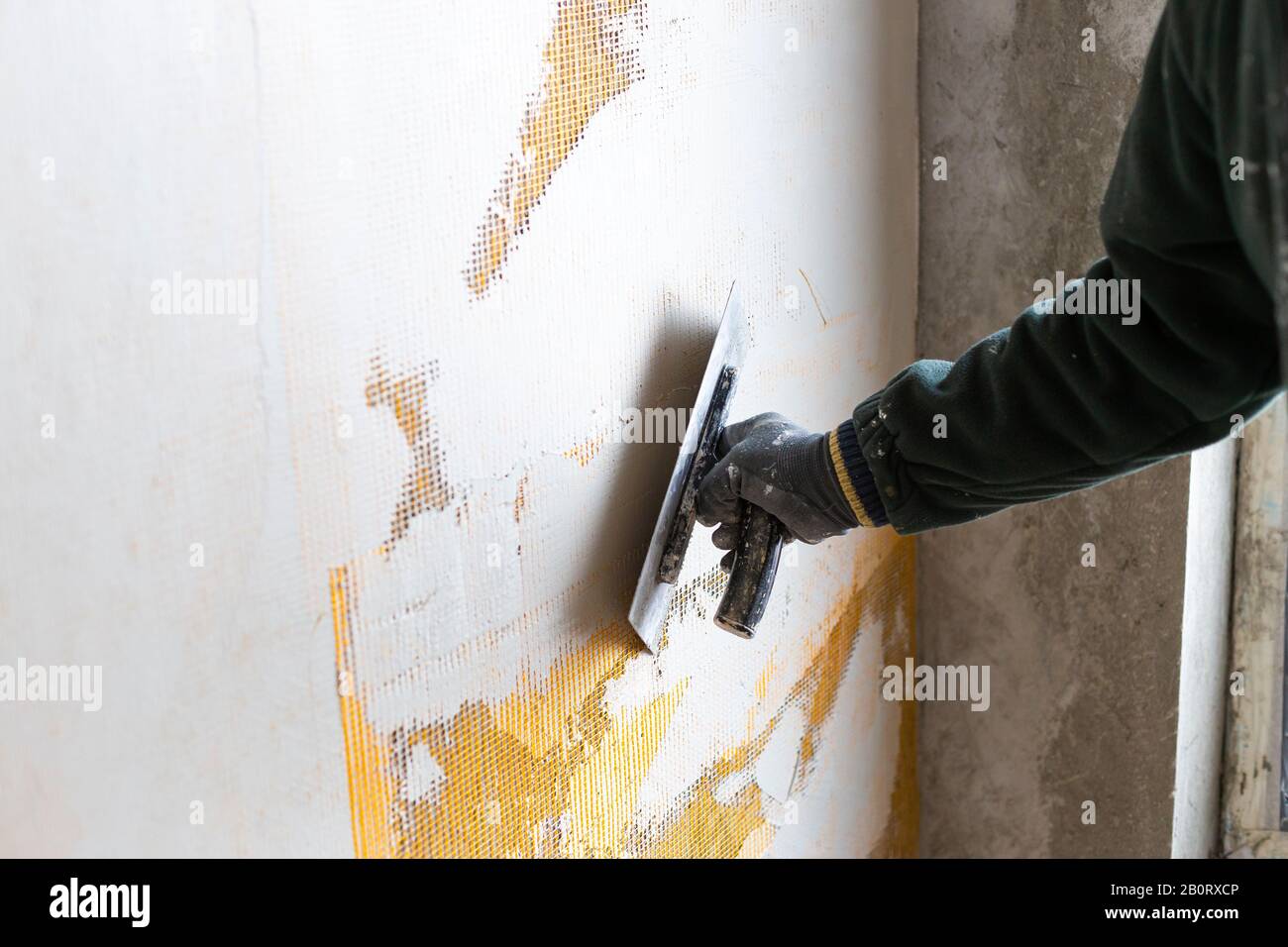 Worker spreading mortar over fiberglass netting (reinforcing mesh ...