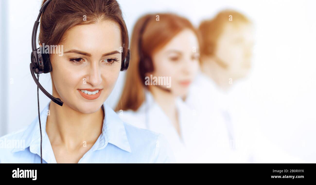 Call center operators. Focus on beautiful business woman using headset ...