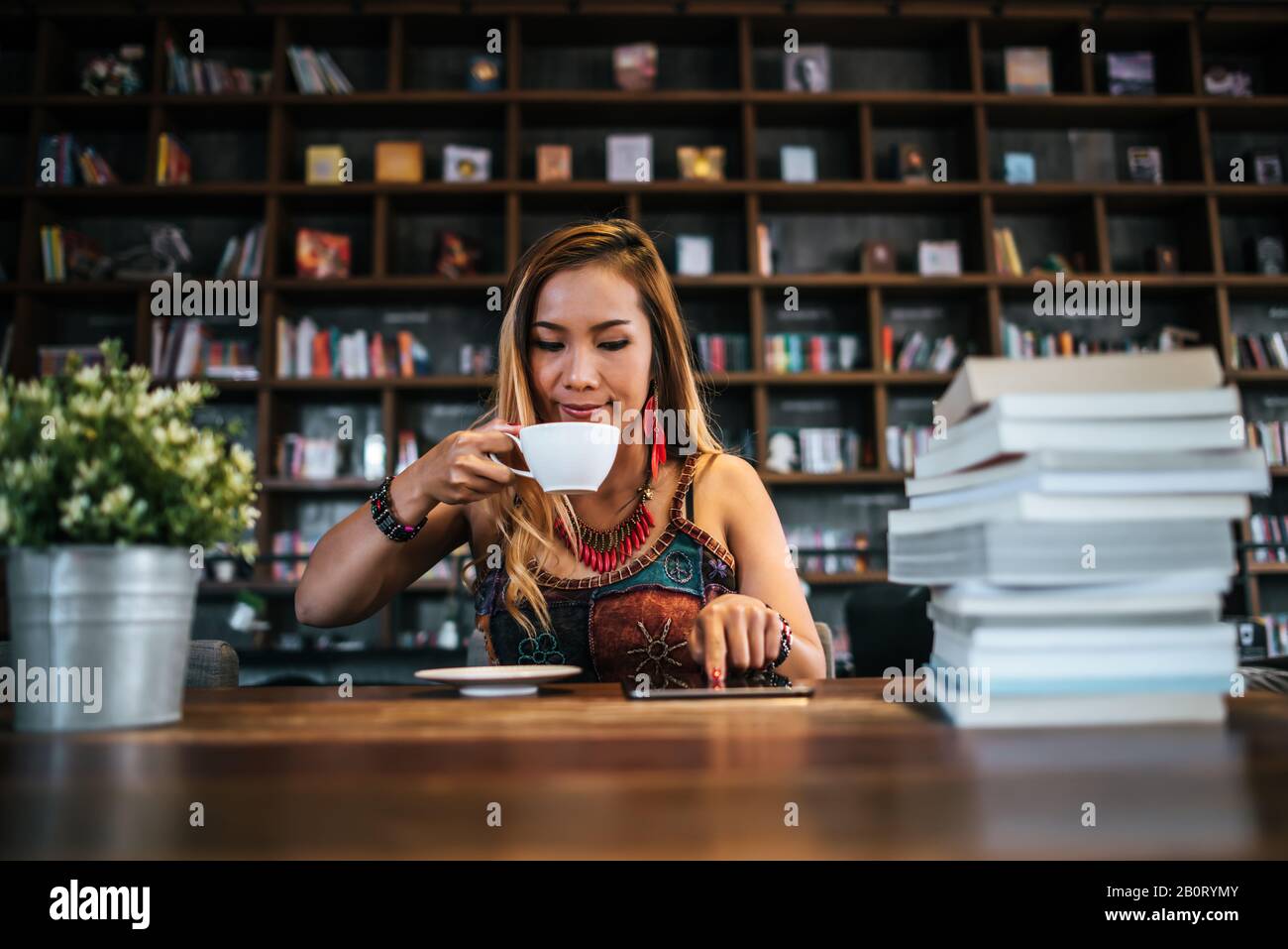 woman is holding a cup of hot cappuccino and reading a book, Business ...