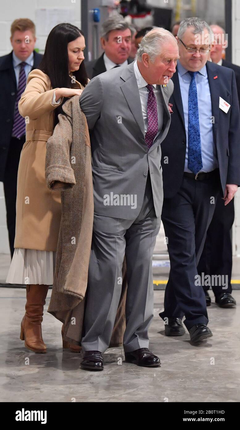 A member of his entourage helps the Prince of Wales put his jacket on ...