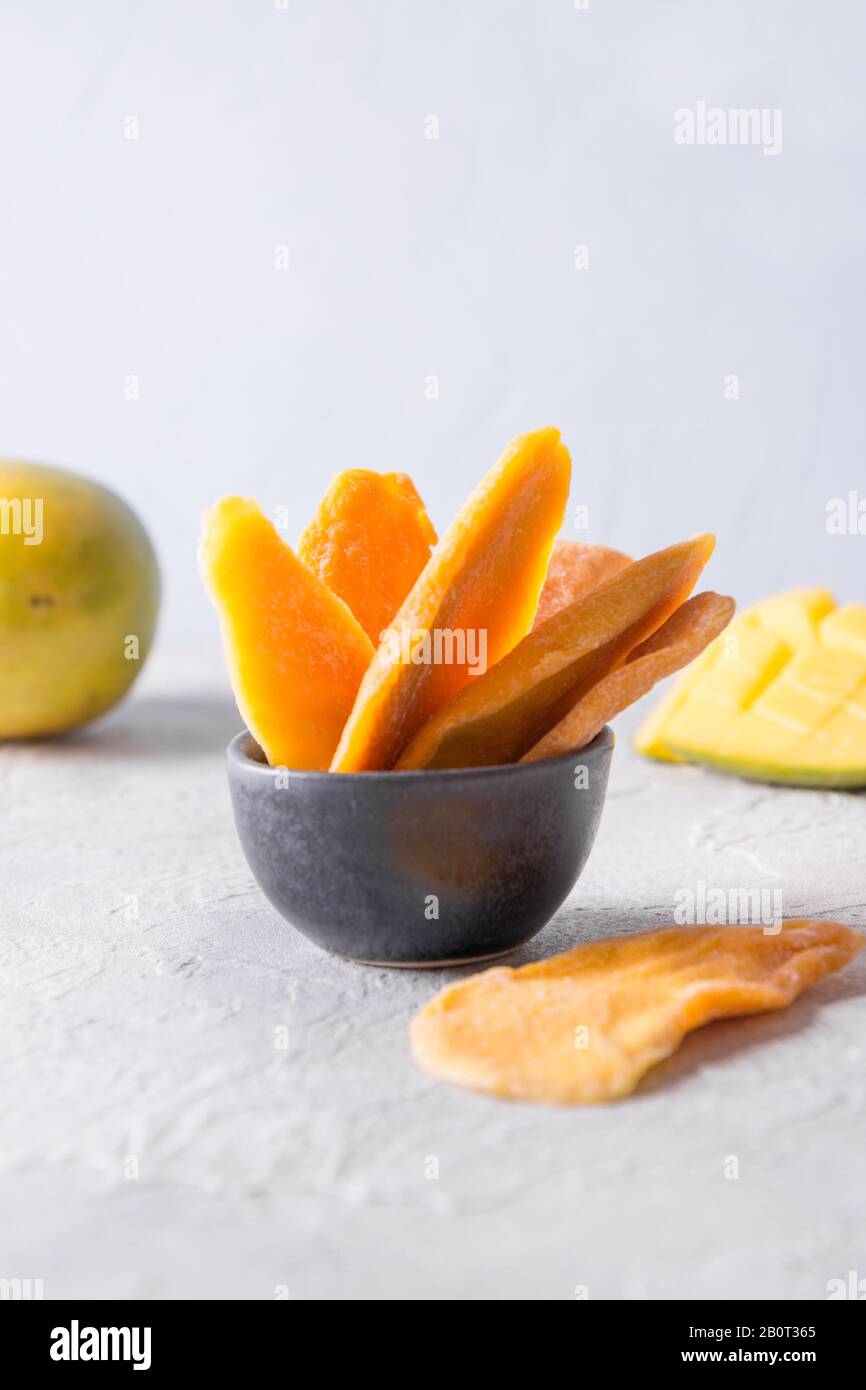 Dehydrated and dried mango chips on light background. Close up. Space ...