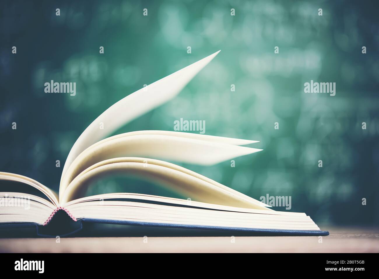 Open book with green board background Stock Photo - Alamy