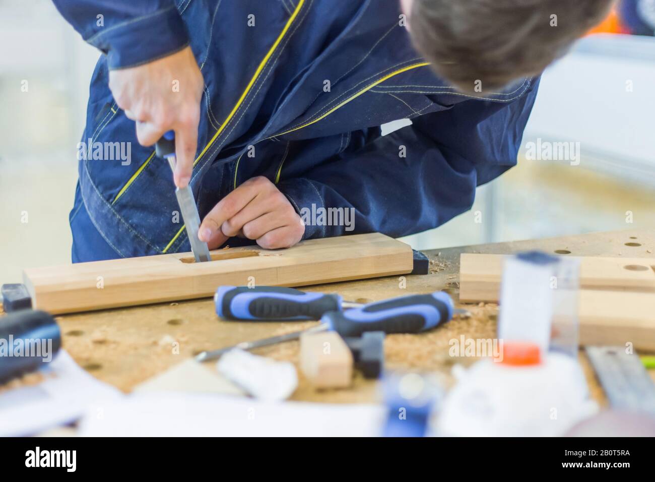 Carpenter using chisel to carve wood on rough workbench at workshop ...