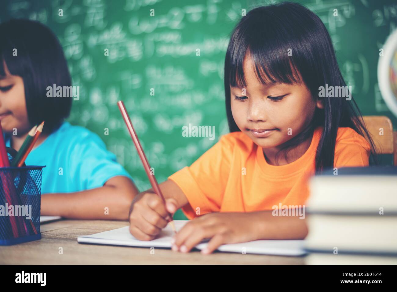 Two girl with crayon drawing at lesson in the classroom Stock Photo - Alamy