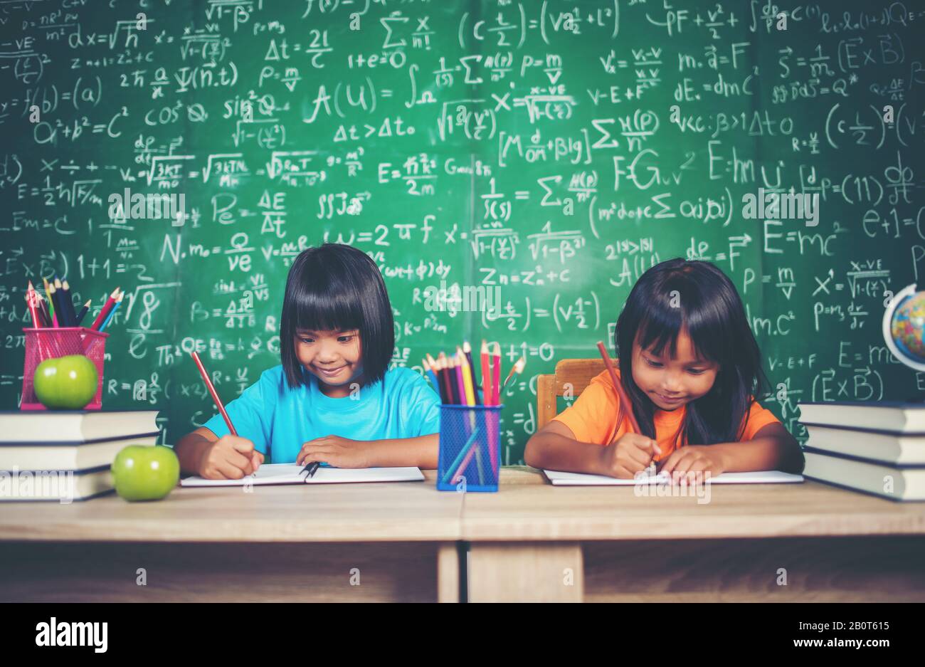 Two girl with crayon drawing at lesson in the classroom Stock Photo - Alamy