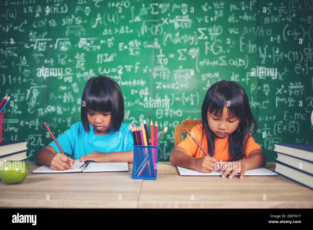 Two girl with crayon drawing at lesson in the classroom Stock Photo - Alamy