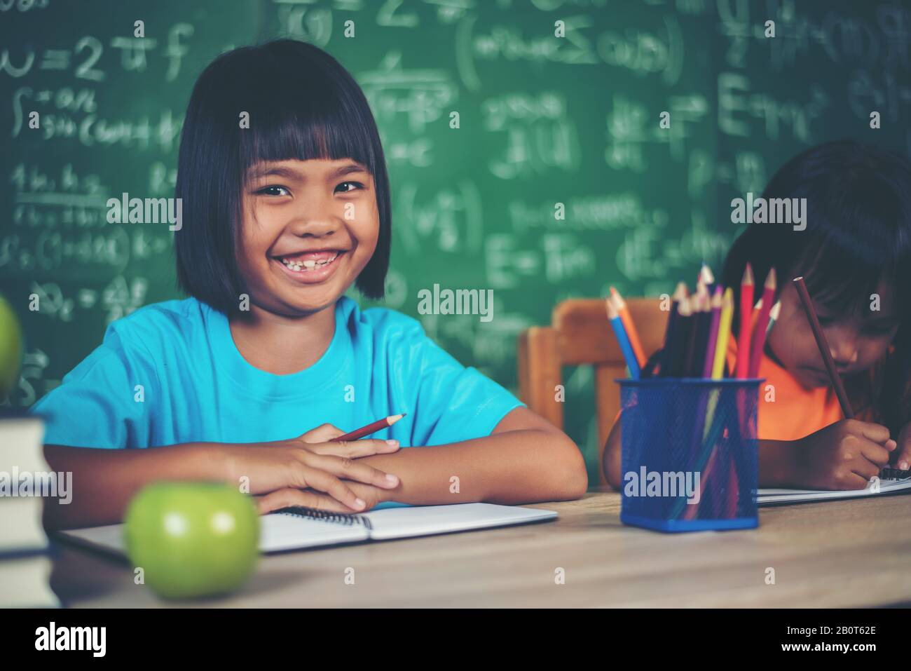 Two girl with crayon drawing at lesson in the classroom Stock Photo - Alamy