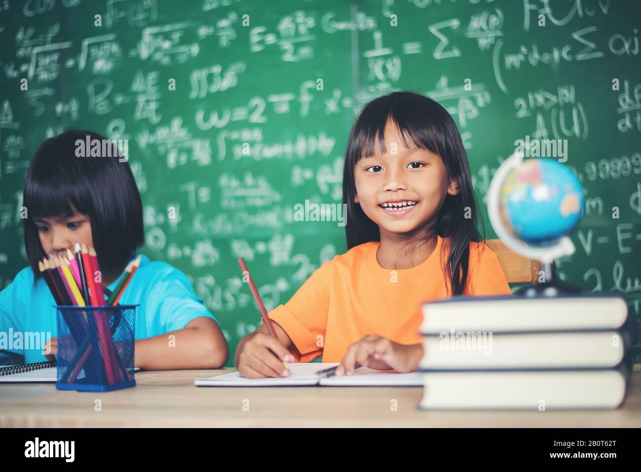 Two girl with crayon drawing at lesson in the classroom Stock Photo - Alamy