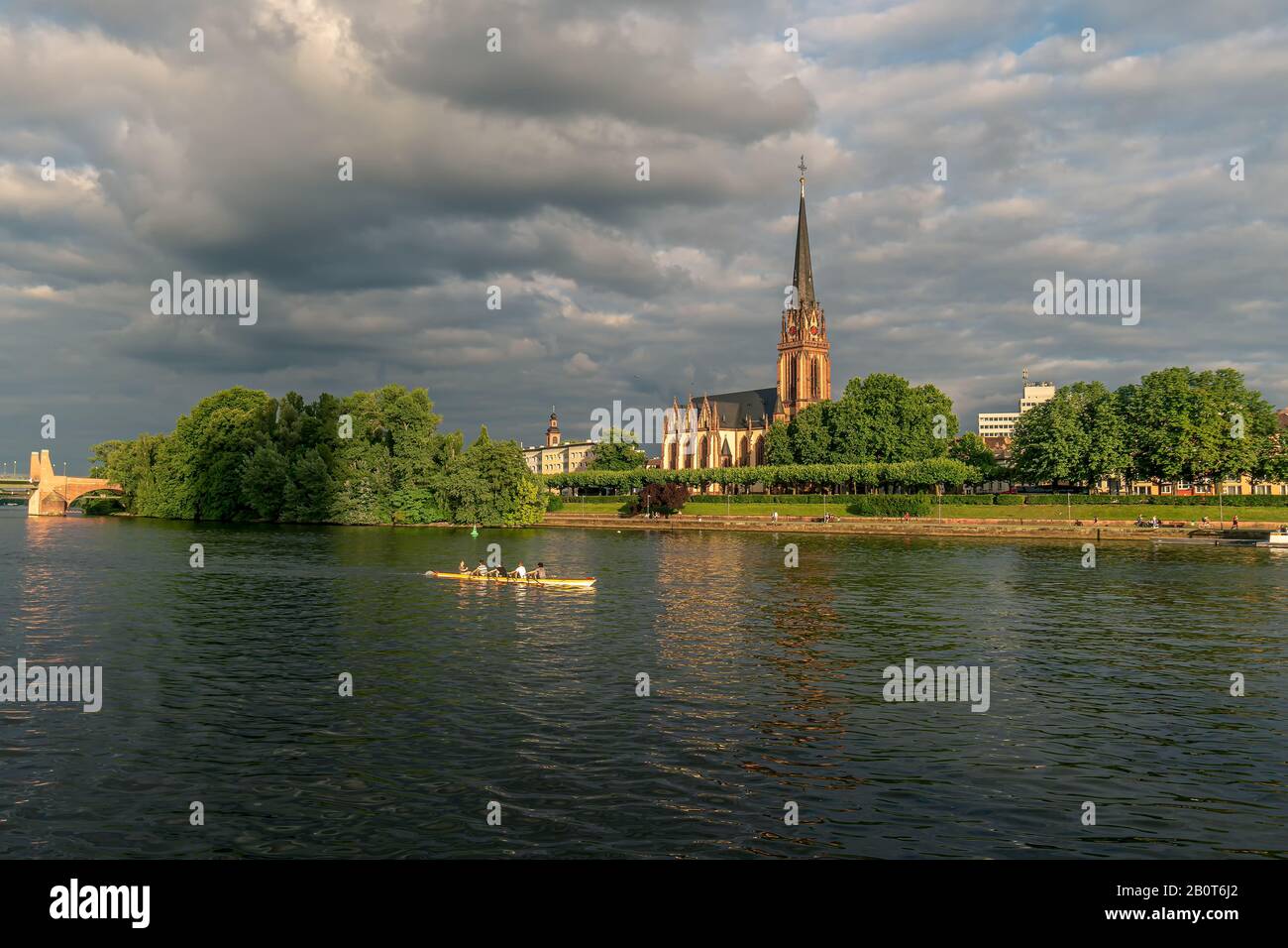 4 man rowing boat on the Main river at Frankfurt with a church in the ...