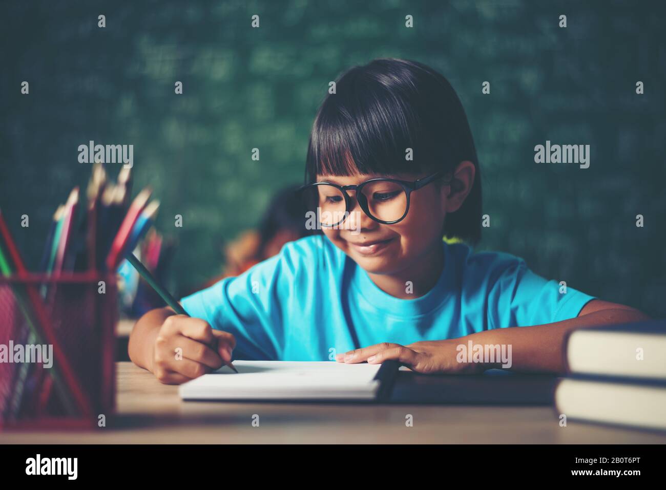 girl with crayon drawing at lesson in the classroom Stock Photo - Alamy