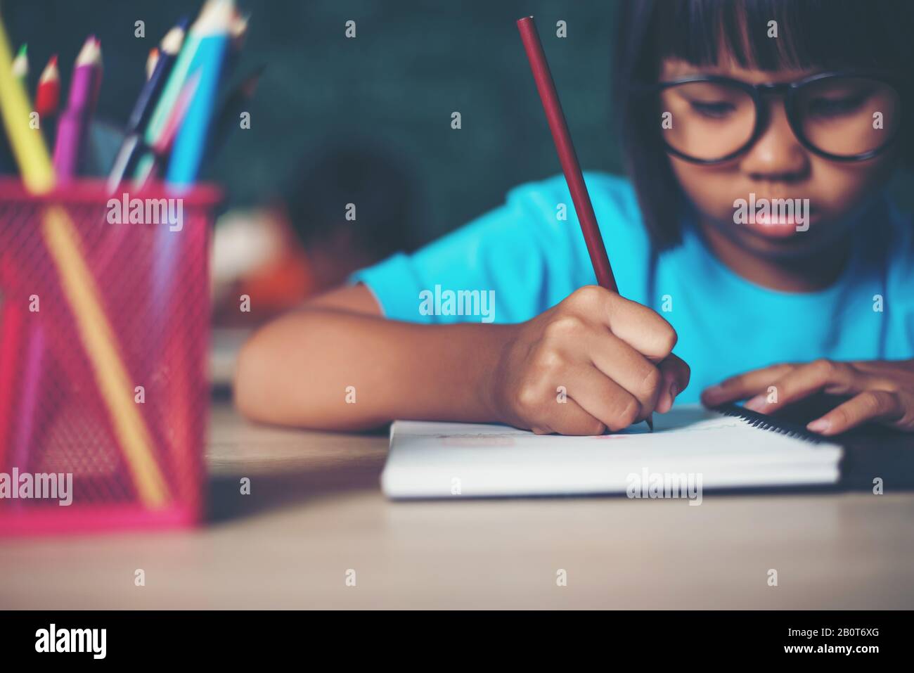 girl with crayon drawing at lesson in the classroom Stock Photo - Alamy
