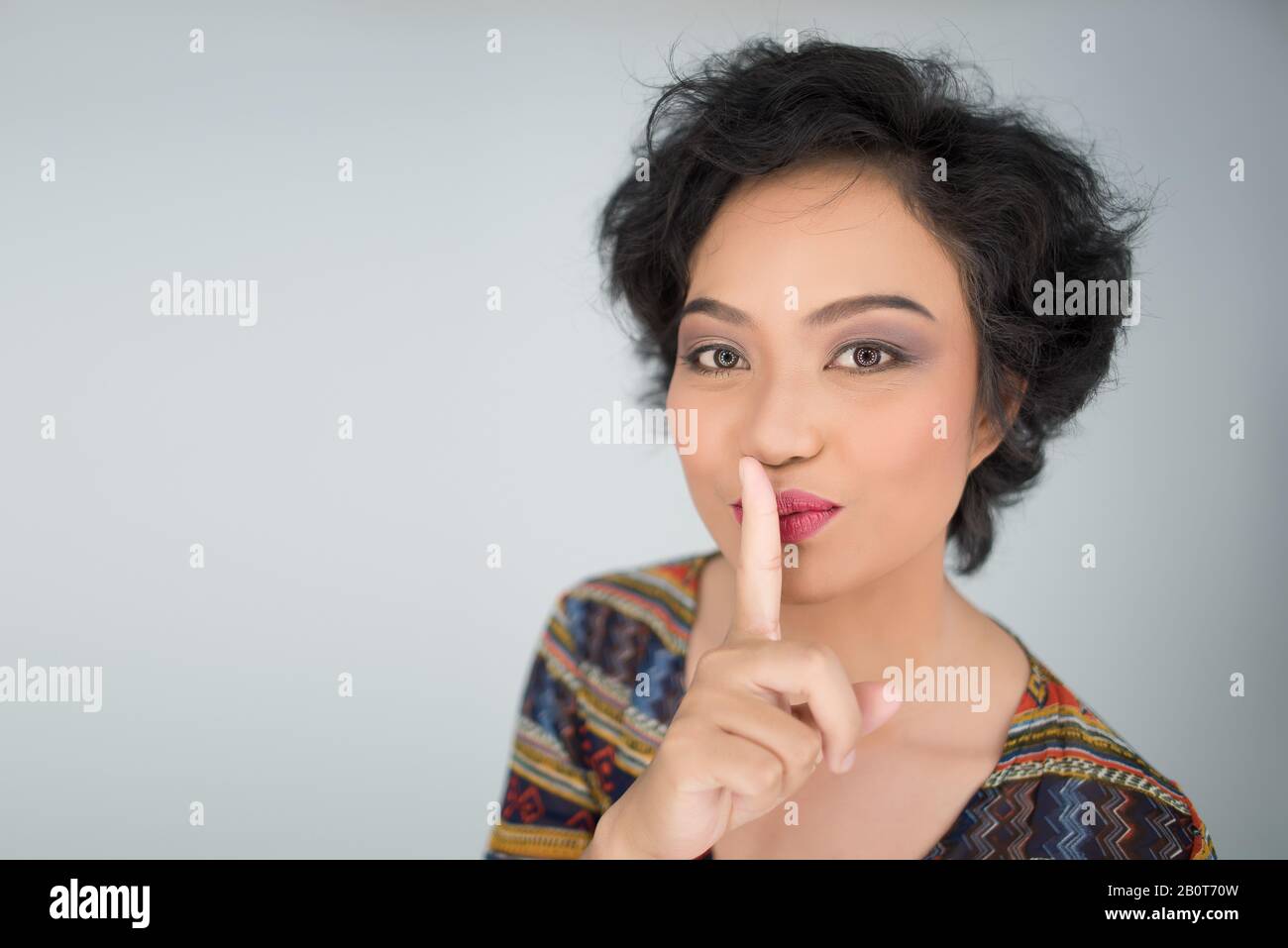 Young girl making silence gesture on white background Stock Photo - Alamy
