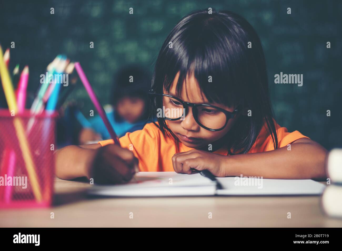 girl with crayon drawing at lesson in the classroom Stock Photo - Alamy