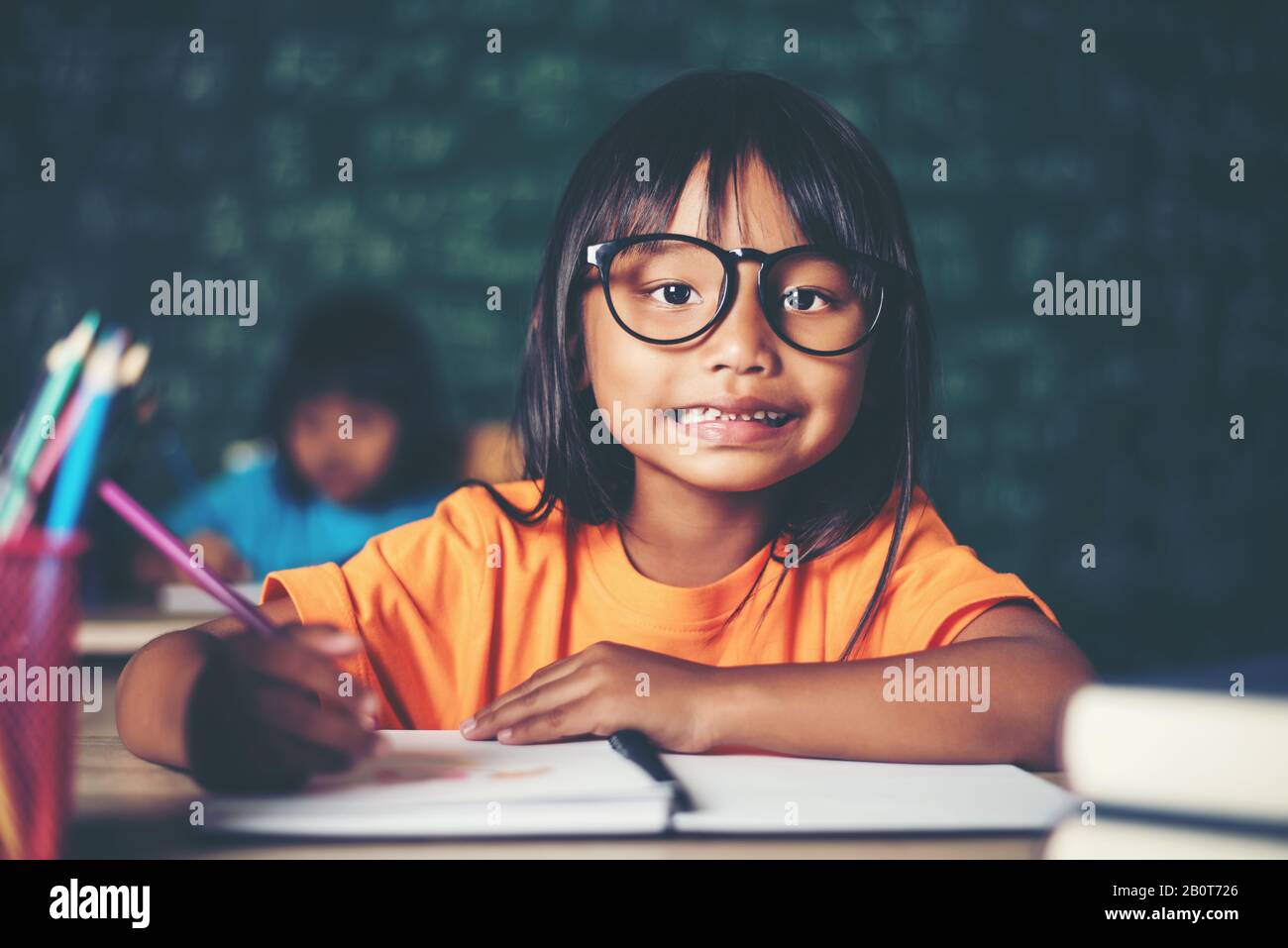girl with crayon drawing at lesson in the classroom Stock Photo - Alamy
