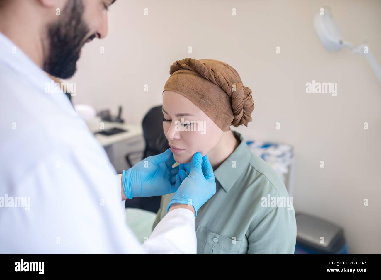 Tall doctor in blue gloves examining his female patient Stock Photo - Alamy
