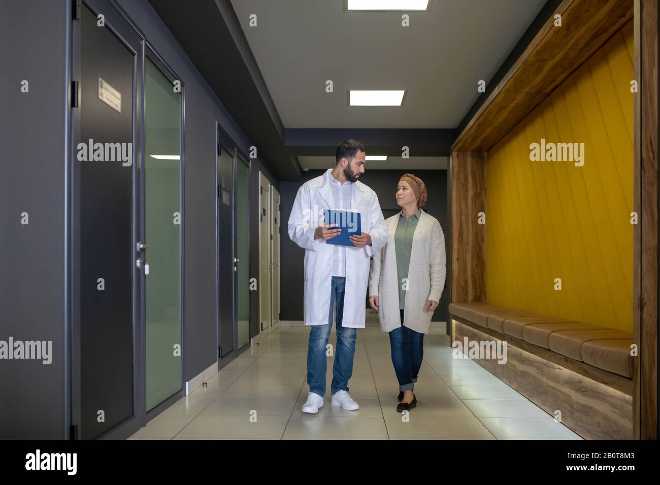 Tall male young doctor walking in corridor with the patient Stock Photo ...