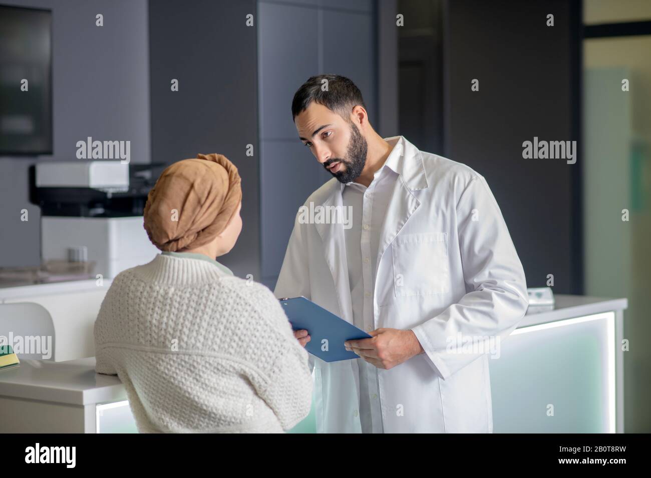 Tall male young doctor talking to a female patient in clinic Stock ...