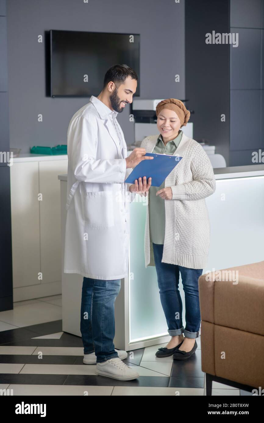 Tall male doctor talking to a female patient Stock Photo - Alamy