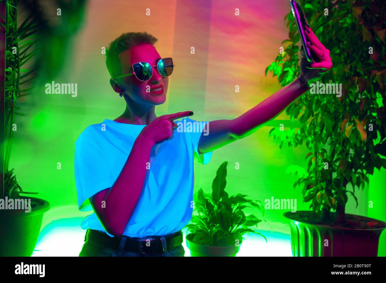 Pointing. Cinematic portrait of stylish woman in neon lighted interior ...