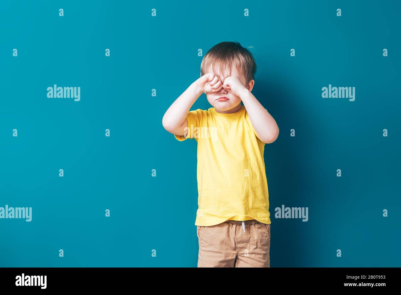 Upset crying sad boy at blue background Stock Photo - Alamy