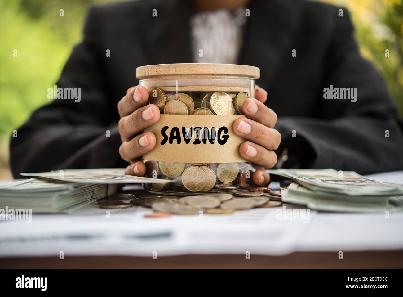 Saving Money putting coins into a jar Stock Photo - Alamy