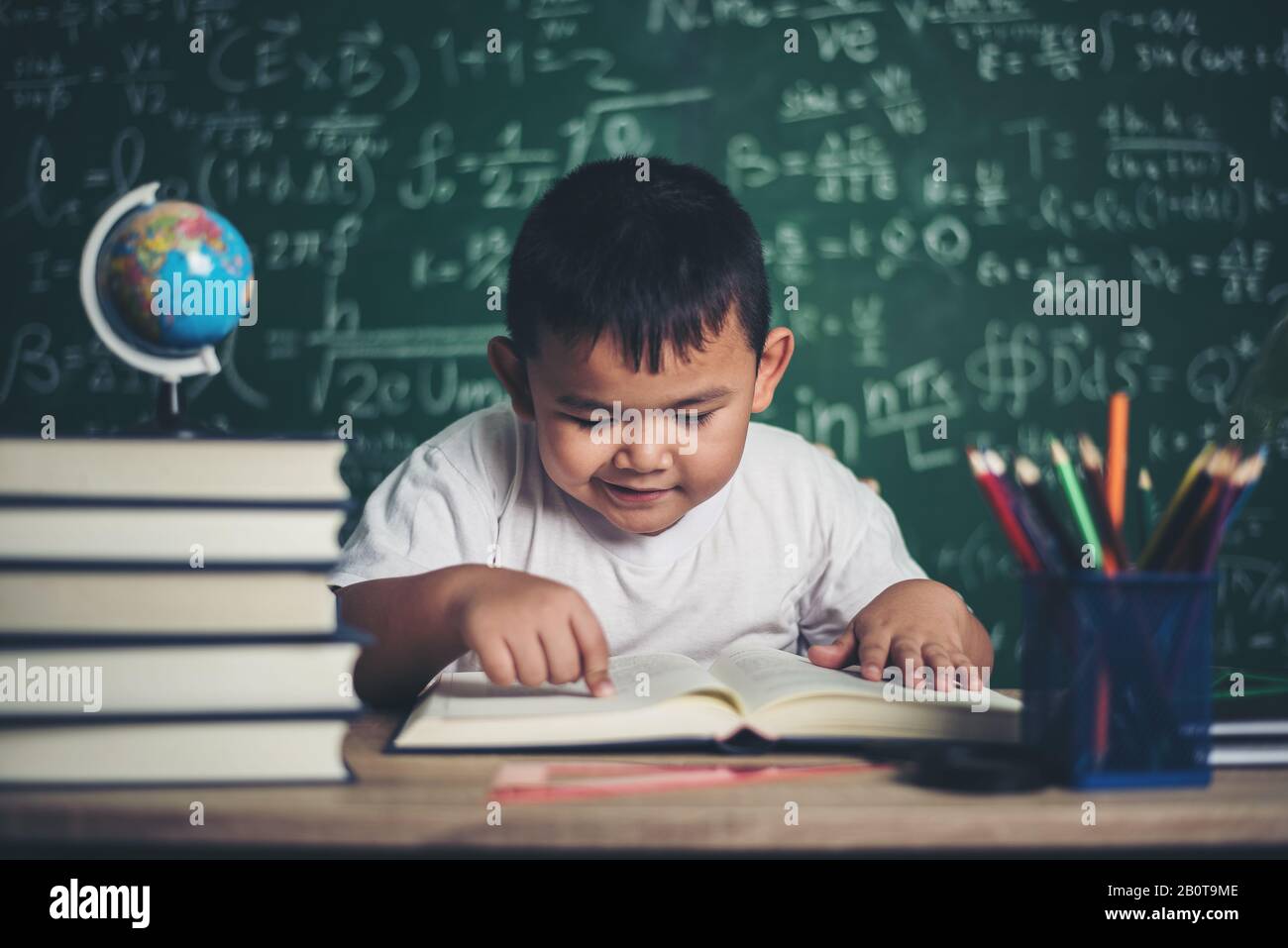 boy reading a book sitting at the table in the classroom Stock Photo ...