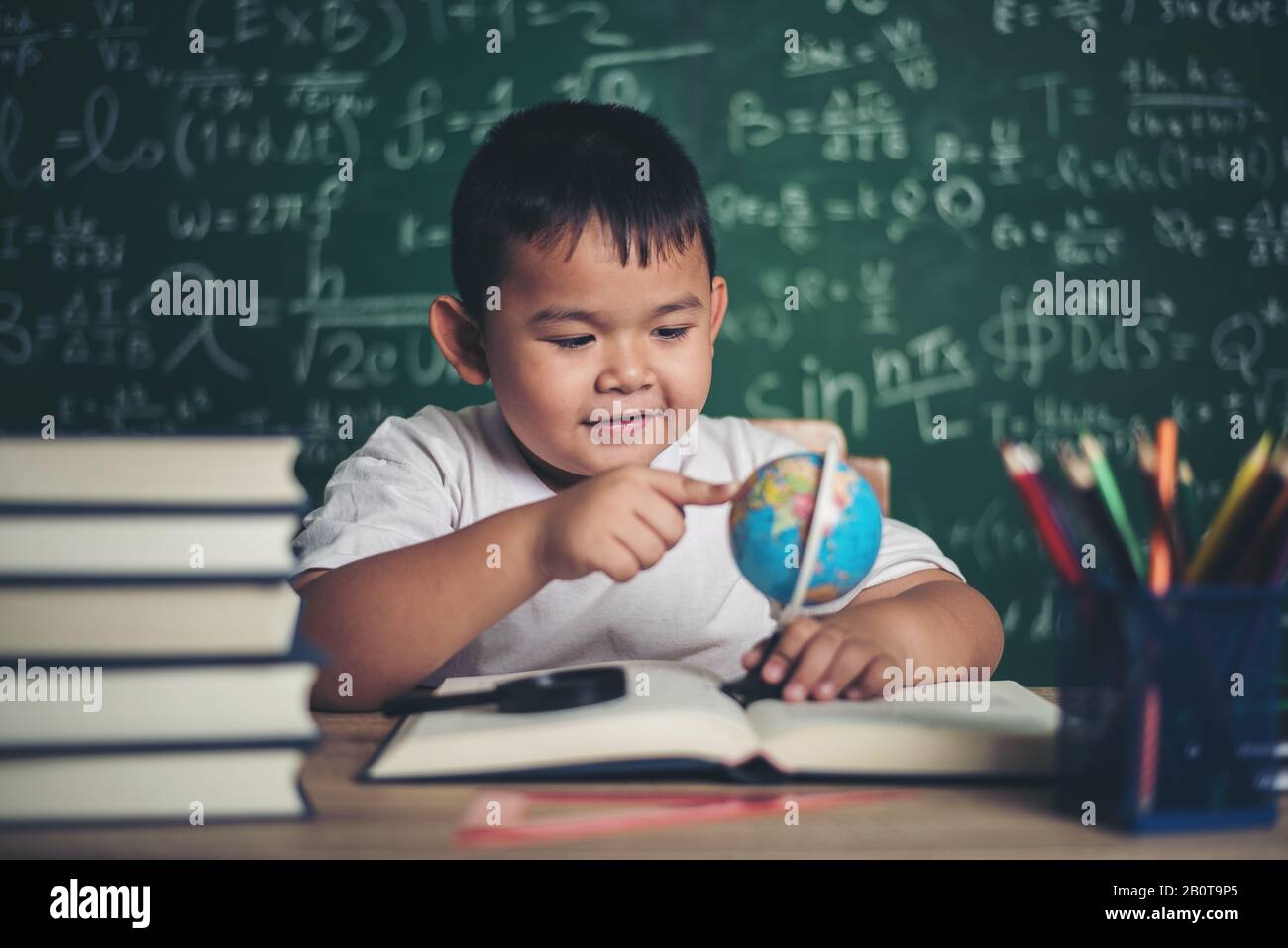 kid observing or studying educational globe model in the classroom ...