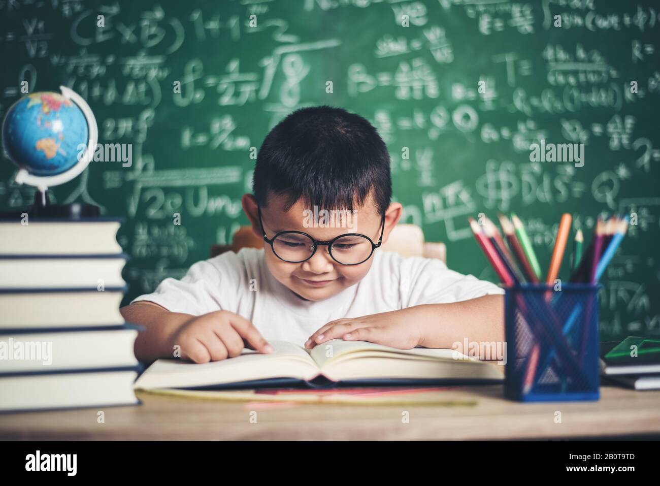 boy reading a book sitting at the table in the classroom Stock Photo ...