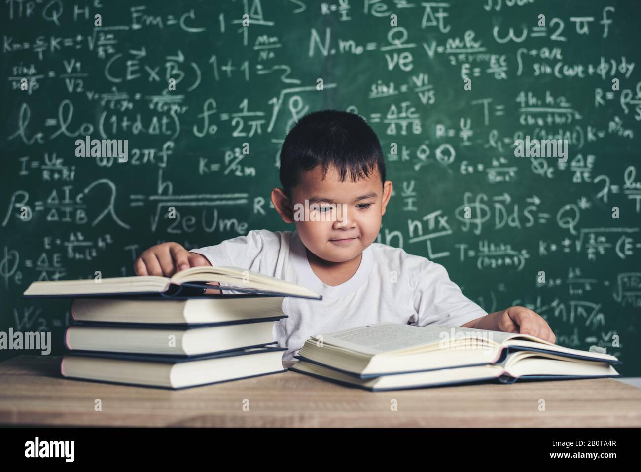boy reading a book sitting at the table in the classroom Stock Photo ...