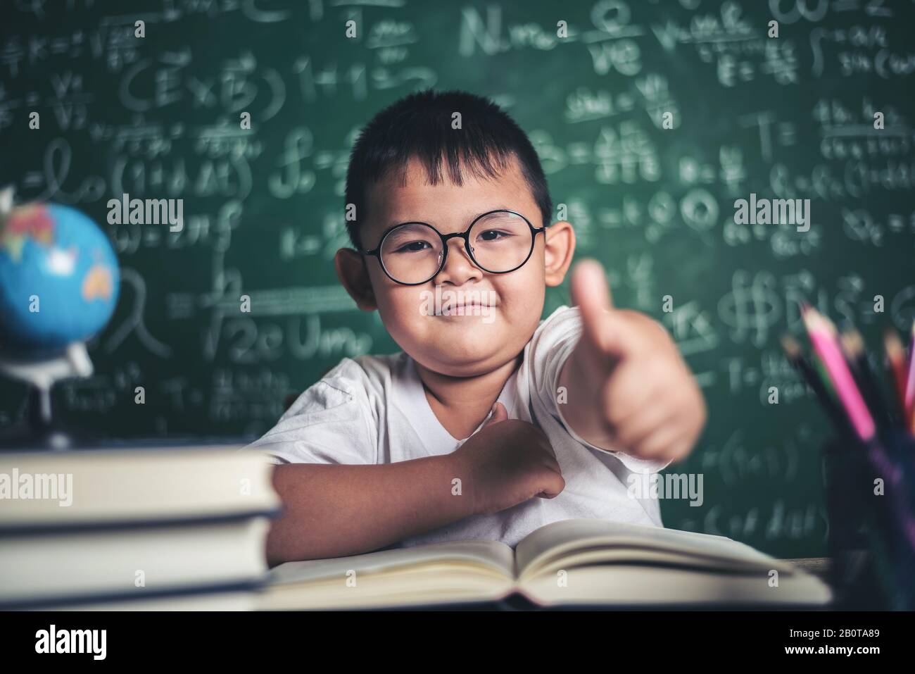 Portrait of a boy with hands thumbs up in the classroom Stock Photo - Alamy