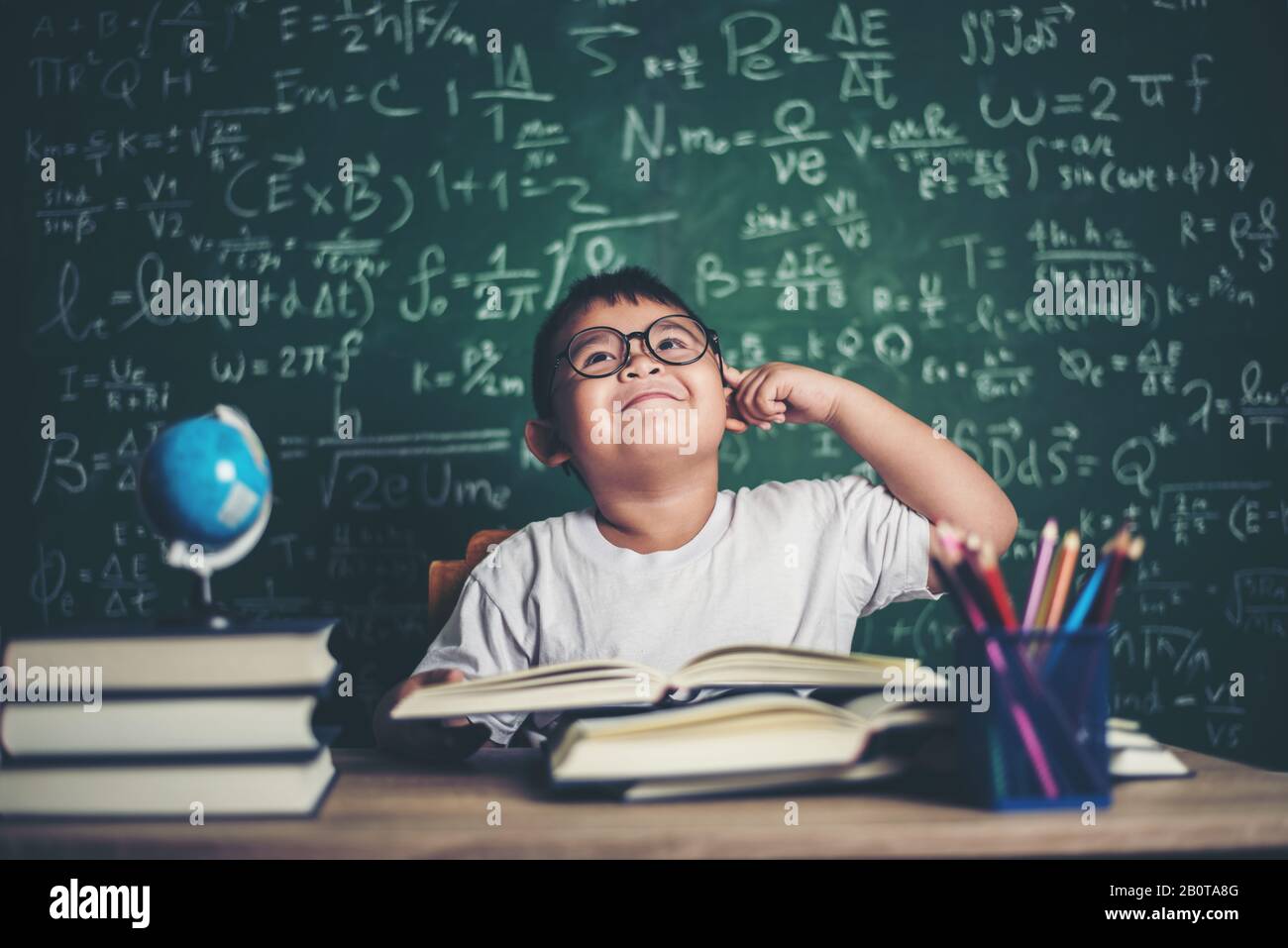Thoughtful little boy with book in the classroom Stock Photo - Alamy
