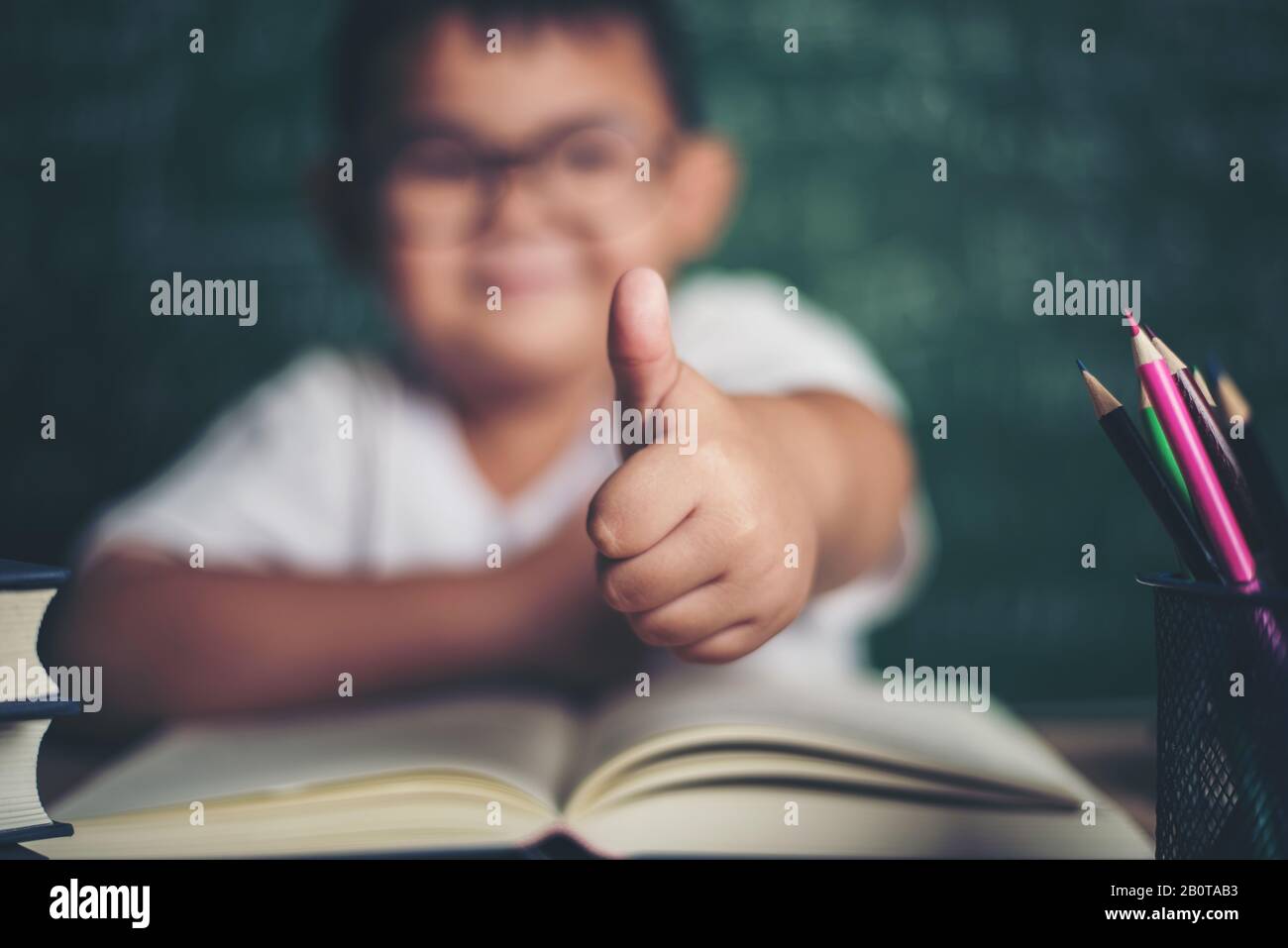 Portrait of a boy with hands thumbs up in the classroom Stock Photo - Alamy