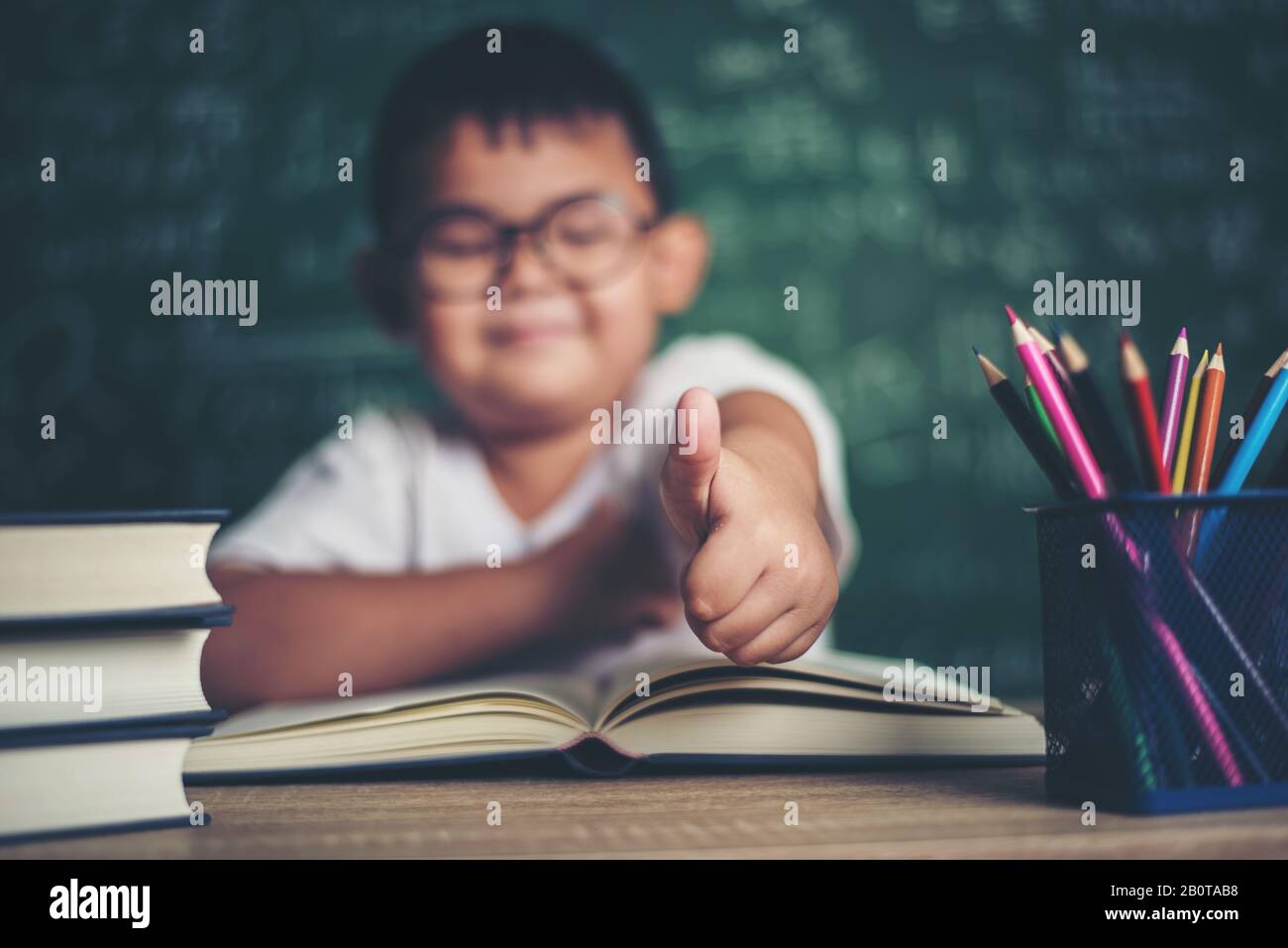 Portrait of a boy with hands thumbs up in the classroom Stock Photo - Alamy