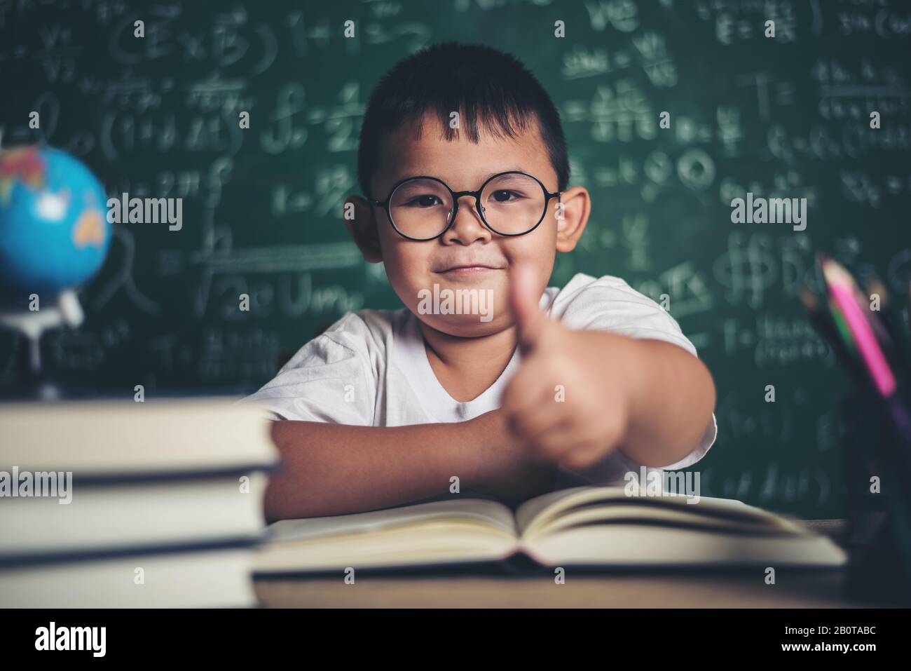 Portrait of a boy with hands thumbs up in the classroom Stock Photo - Alamy
