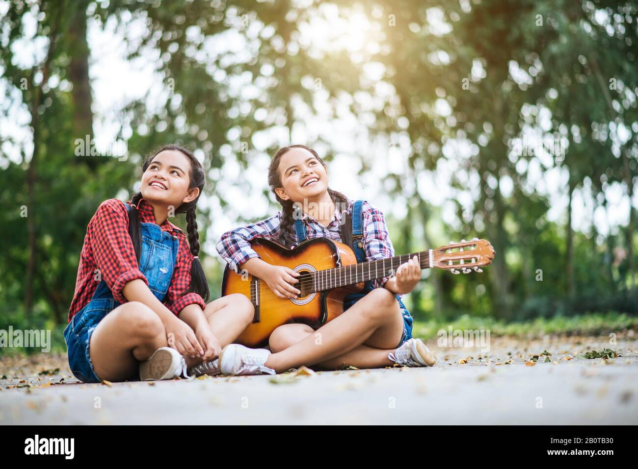 Two girl relax playing guitar and sing a song Stock Photo - Alamy